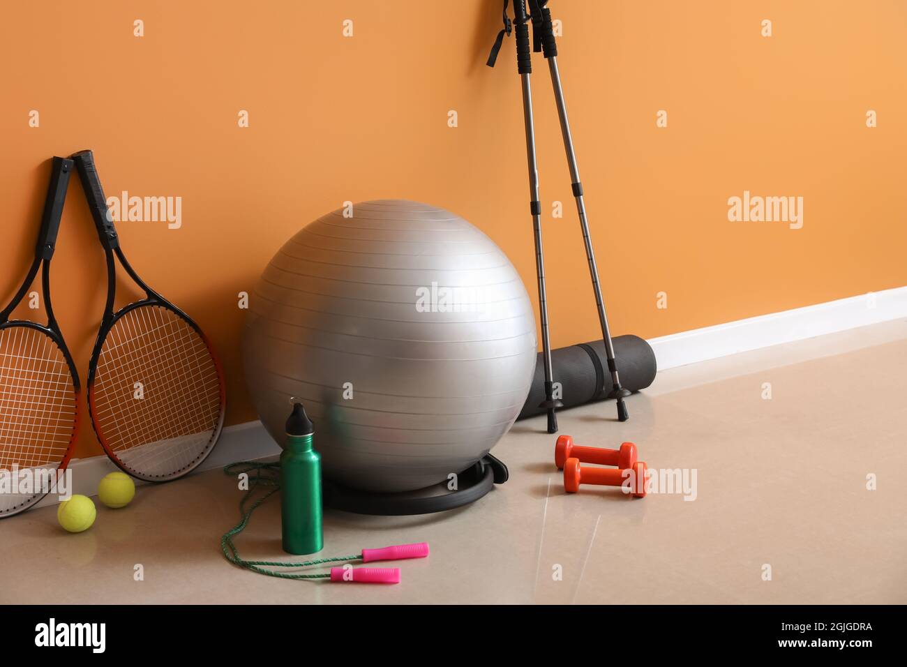 Set of sports equipment on floor near color wall Stock Photo - Alamy