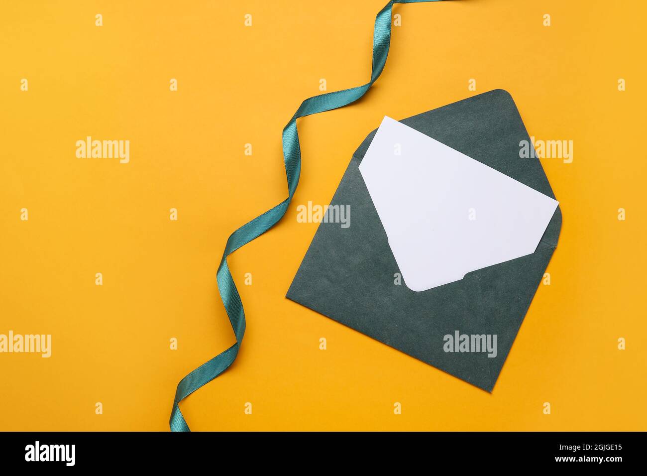 Envelope with blank card and ribbon on color background Stock Photo - Alamy