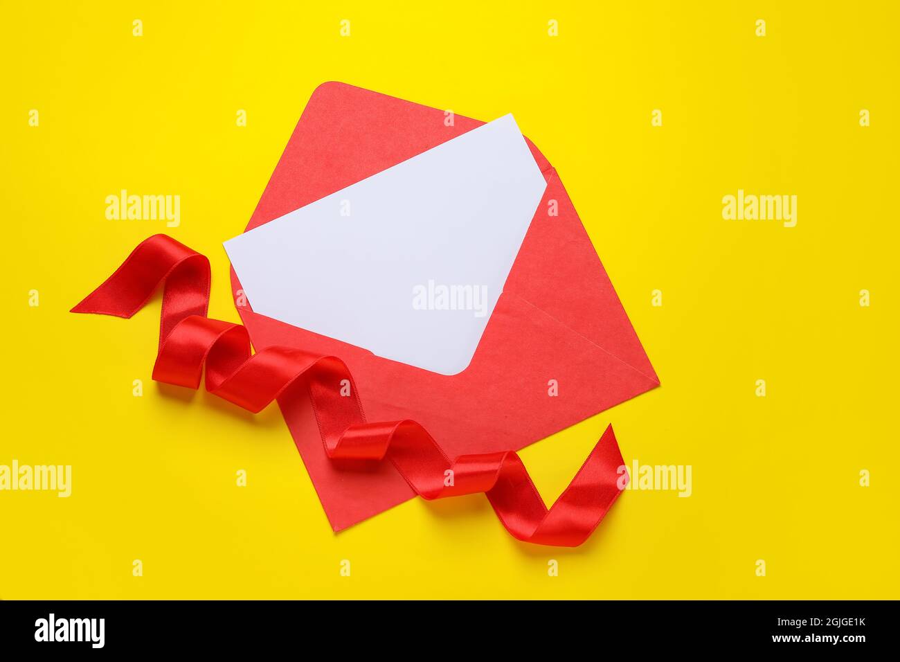 Envelope with blank card and ribbon on color background Stock Photo - Alamy