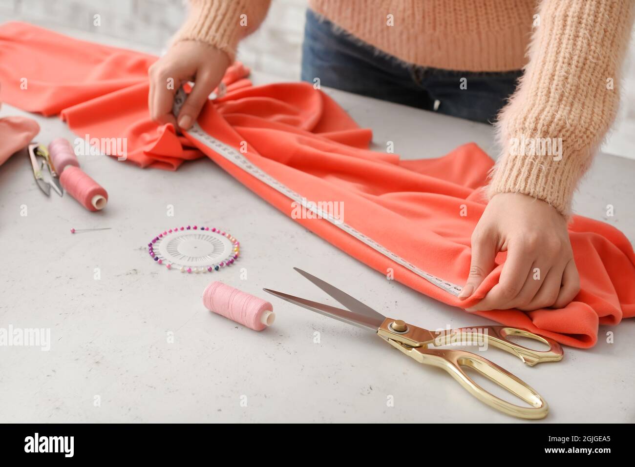 Young woman measuring fabric in studio Stock Photo - Alamy