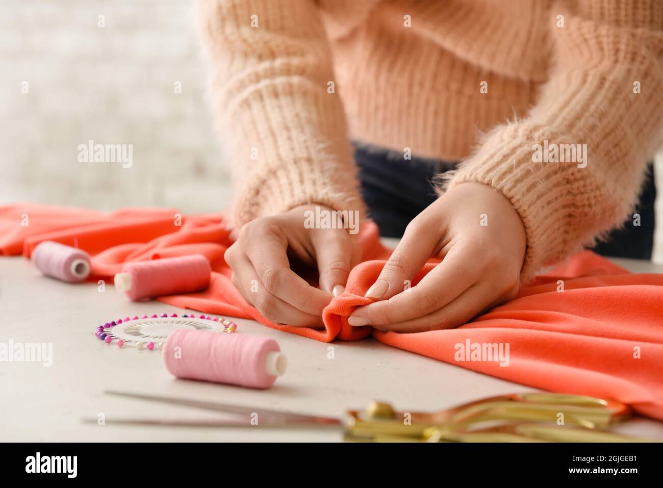 Young woman sewing clothes in studio Stock Photo - Alamy