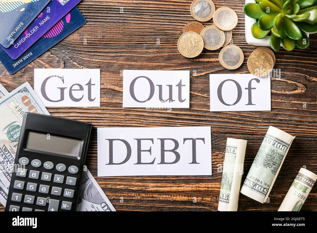 Composition with text GET OUT OF DEBT and money on wooden background ...