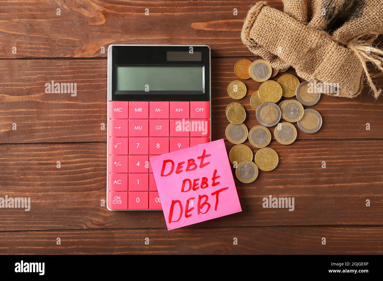 Paper with words DEBT, calculator and coins on wooden background Stock ...