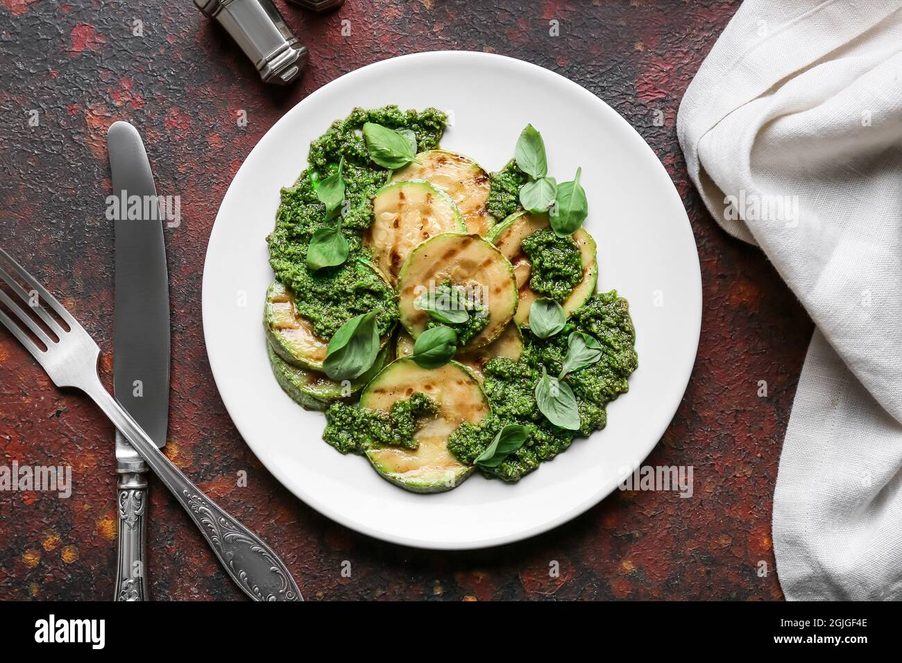 Plate with tasty grilled squash and pesto sauce on color background ...