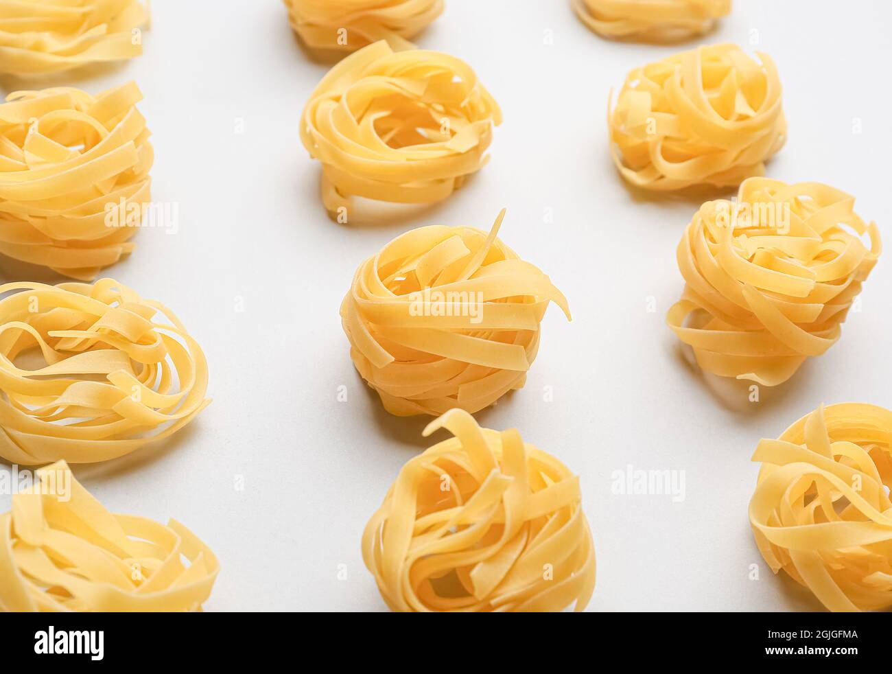 Uncooked tagliatelle pasta on light background Stock Photo - Alamy