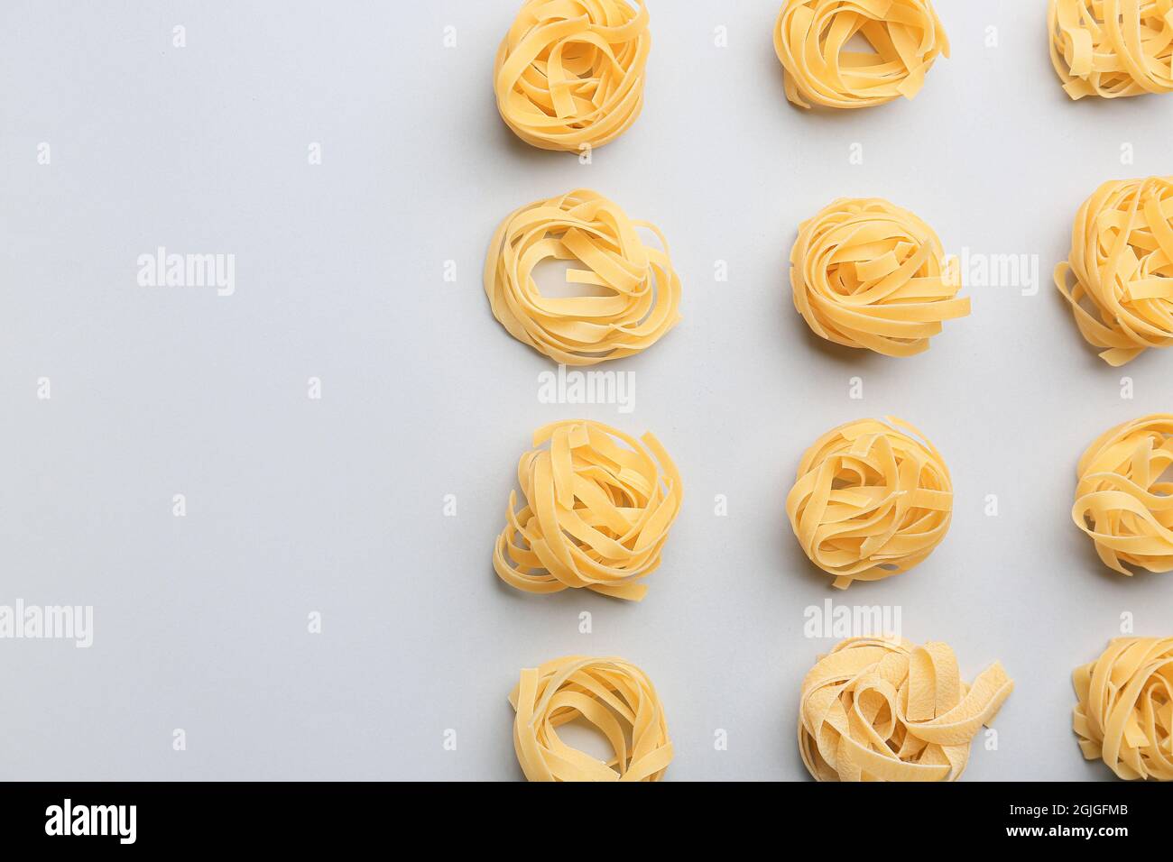 Uncooked tagliatelle pasta on light background Stock Photo - Alamy