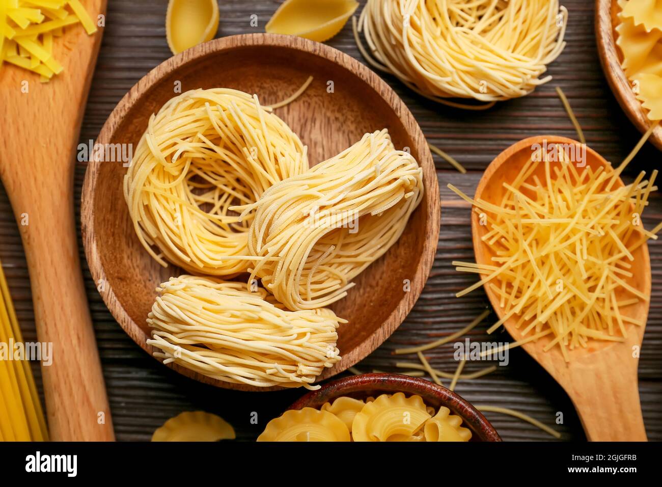 Different types of uncooked pasta on dark wooden background Stock Photo ...