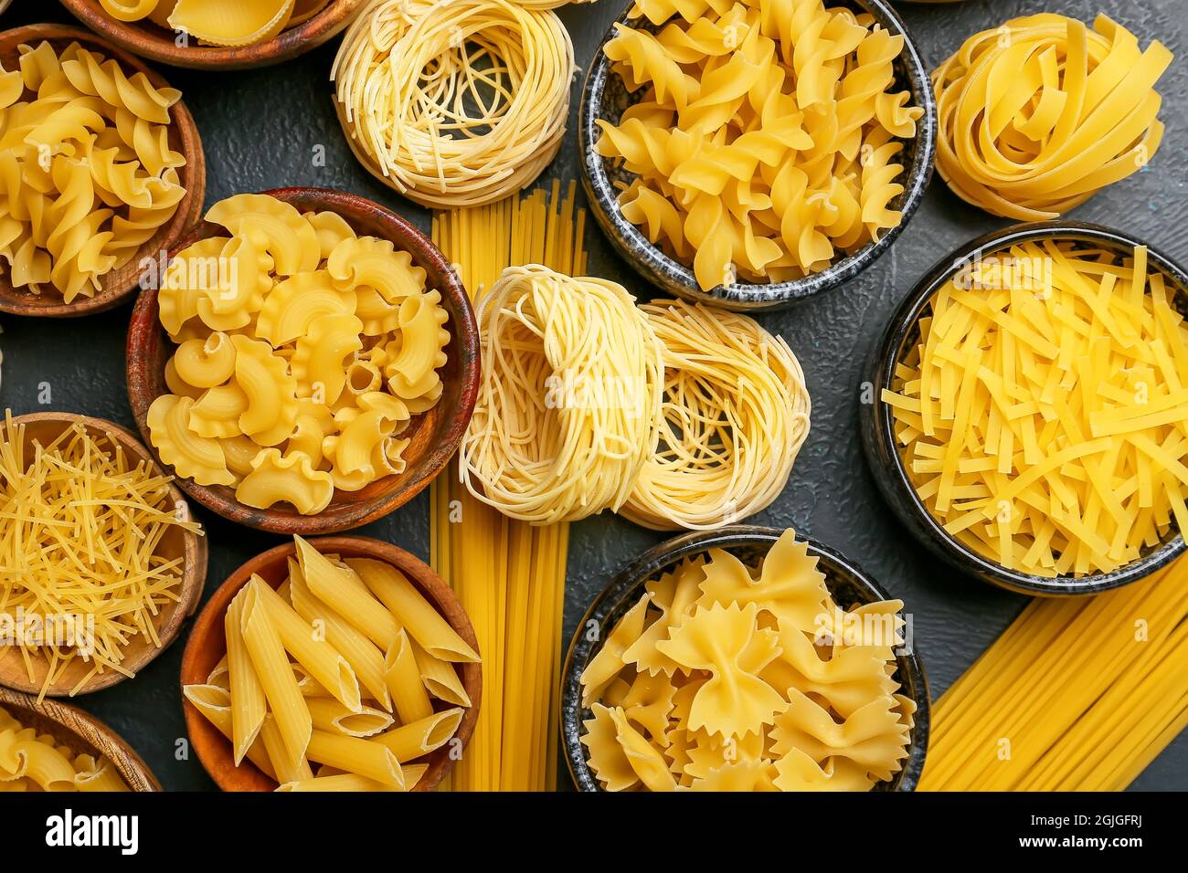 Different types of uncooked pasta on dark background Stock Photo - Alamy
