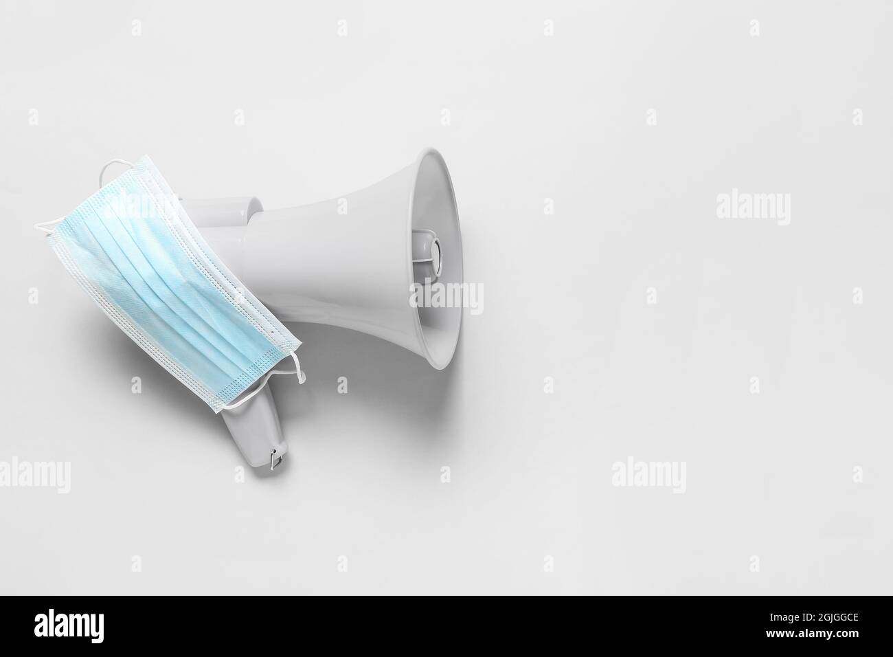 Modern megaphone with medical mask on light background Stock Photo - Alamy