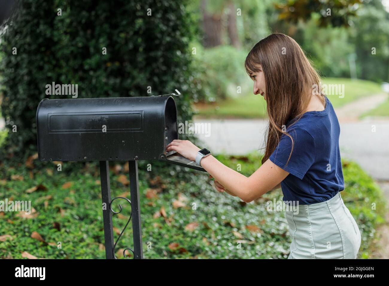 A teen brunette girl with long hair checking the mailbox for letters ...