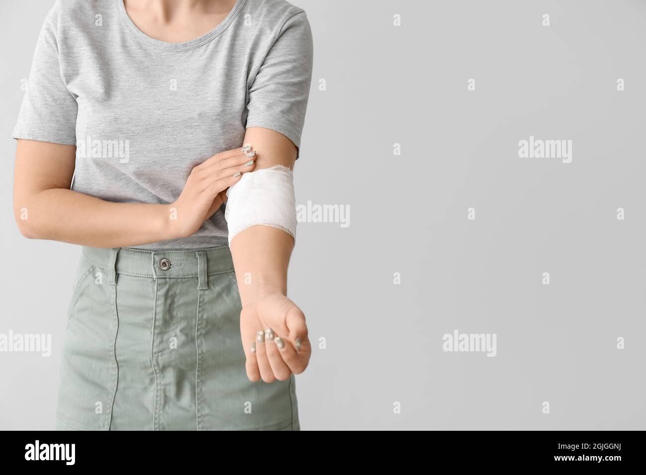 Young woman with bandaged arm on light background Stock Photo - Alamy