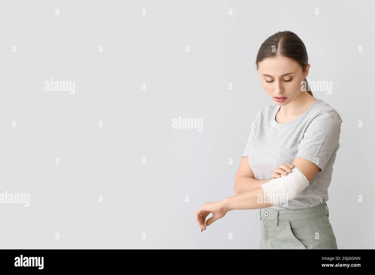 Young woman with bandaged arm on light background Stock Photo - Alamy