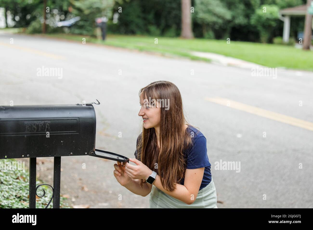A teen brunette girl with long hair checking the mailbox for letters ...