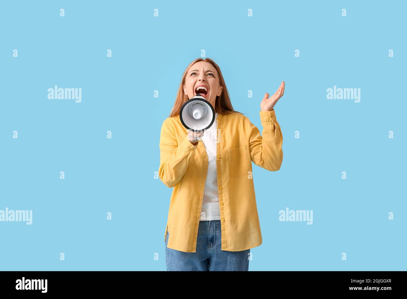Angry mature woman shouting into megaphone on color background Stock ...