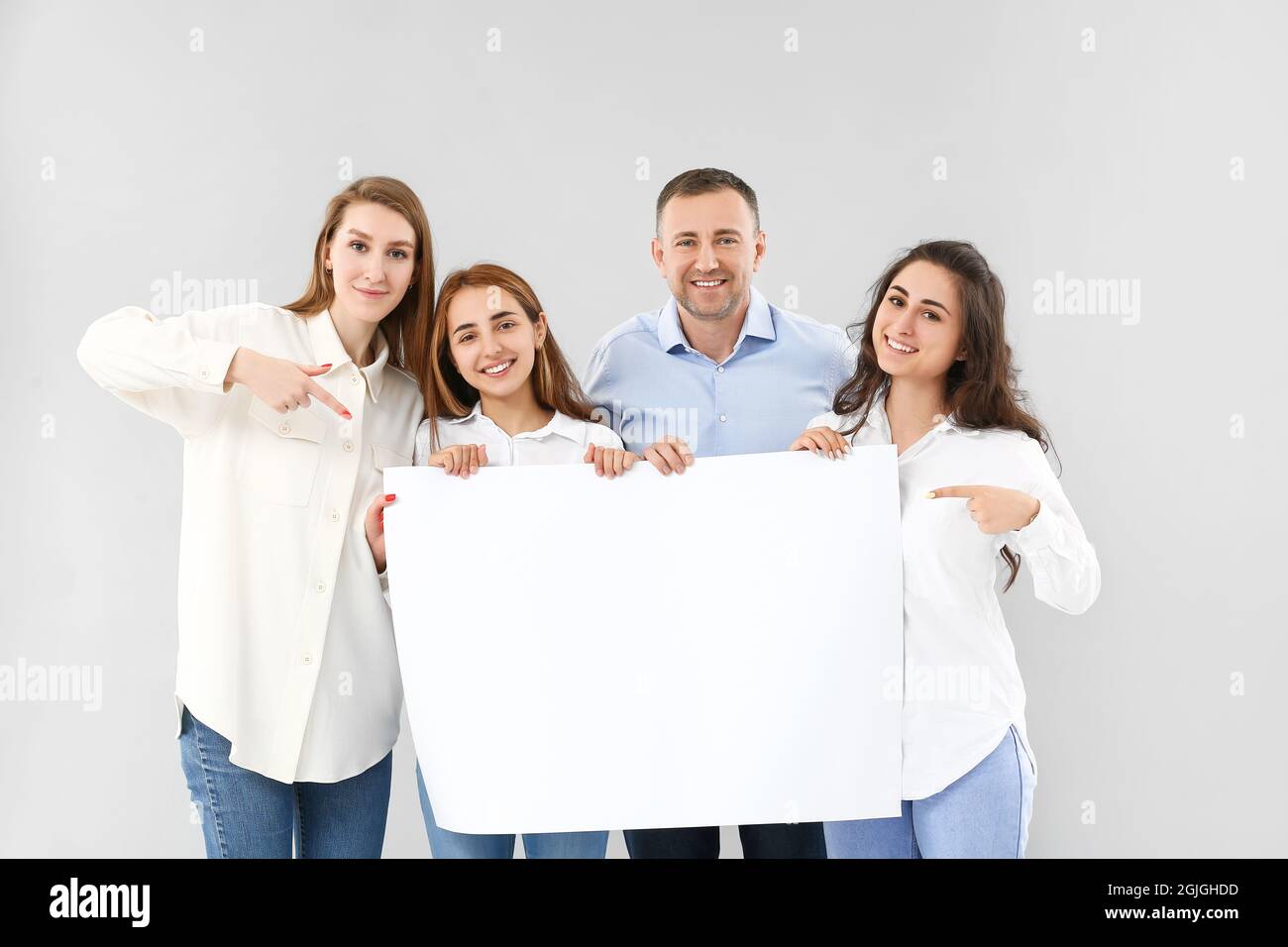 Group of people with blank poster on light background Stock Photo - Alamy