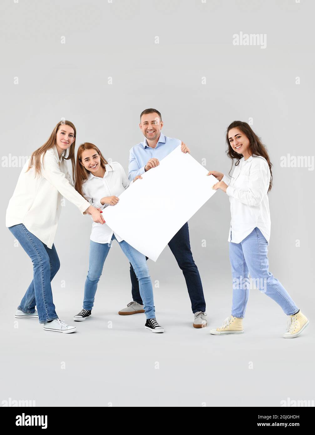 Group of people with blank poster on light background Stock Photo - Alamy