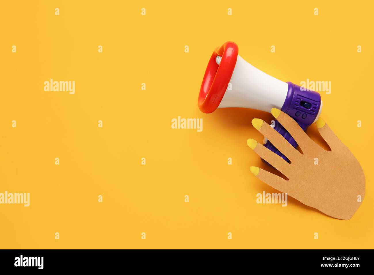 Toy megaphone with paper hand on color background Stock Photo - Alamy