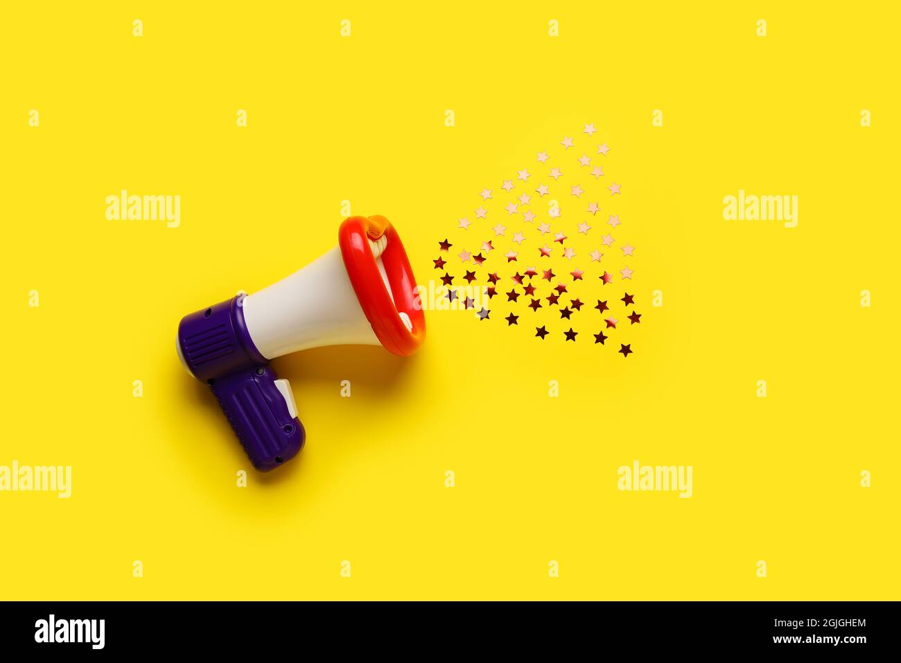 Toy megaphone with confetti on color background Stock Photo - Alamy