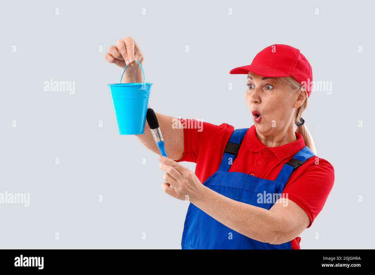 Shocked female painter with bucket and brush on light background Stock ...