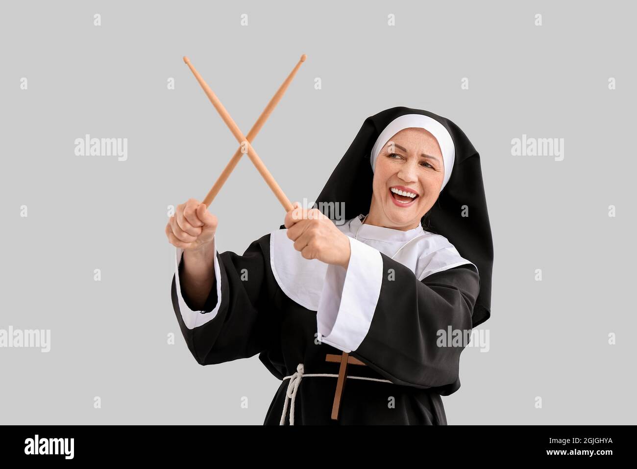 Mature nun with drum sticks on light background Stock Photo - Alamy