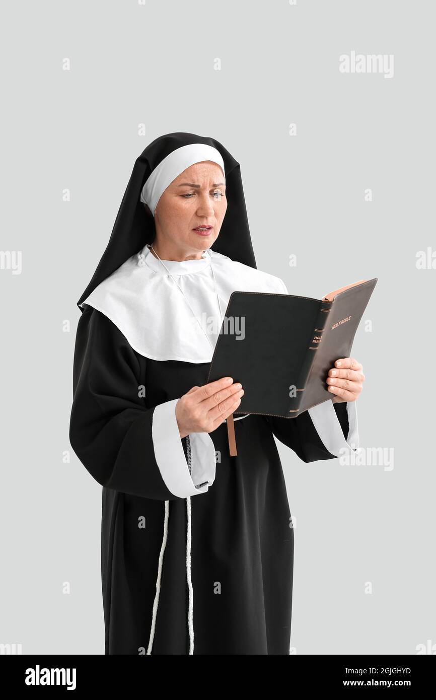 Mature nun reading Holy Bible on light background Stock Photo - Alamy
