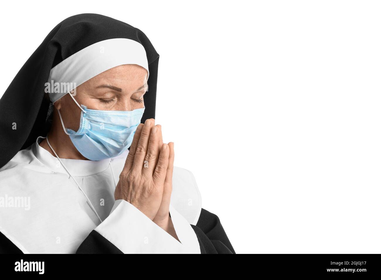 Mature nun in medical mask praying on white background Stock Photo - Alamy