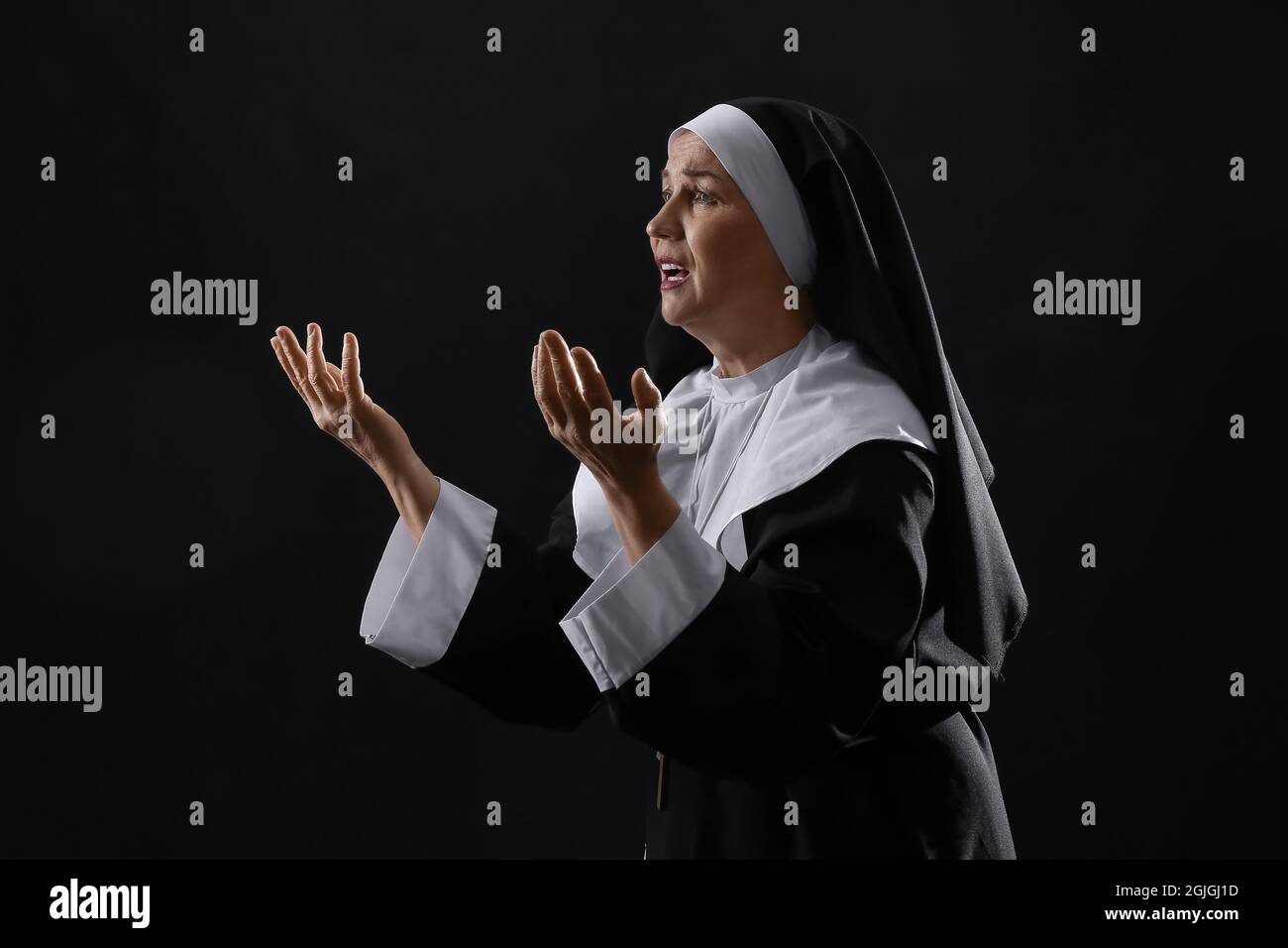 Upset mature nun on dark background Stock Photo - Alamy