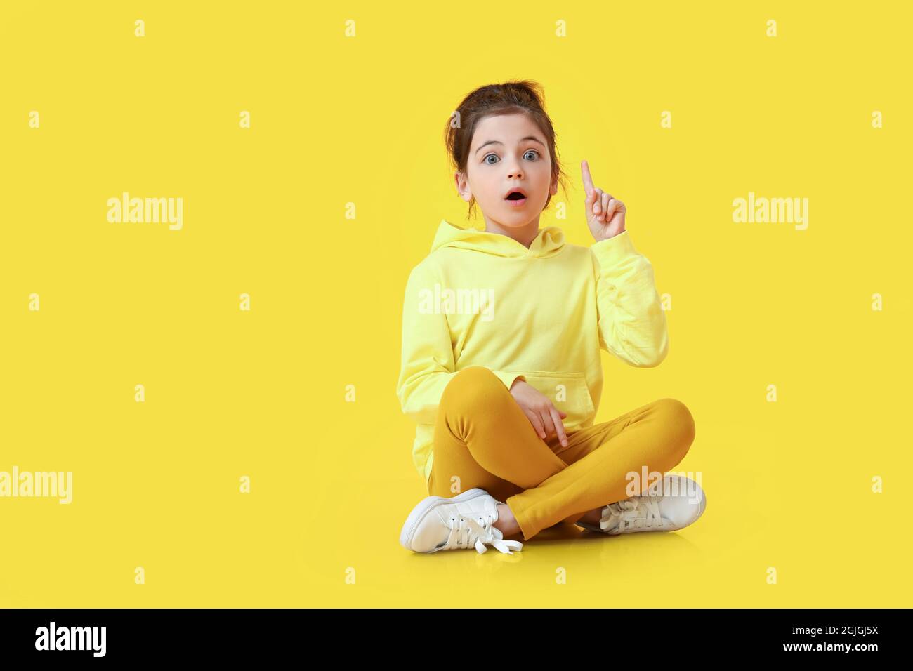 Cute little girl with raised index finger on color background Stock ...