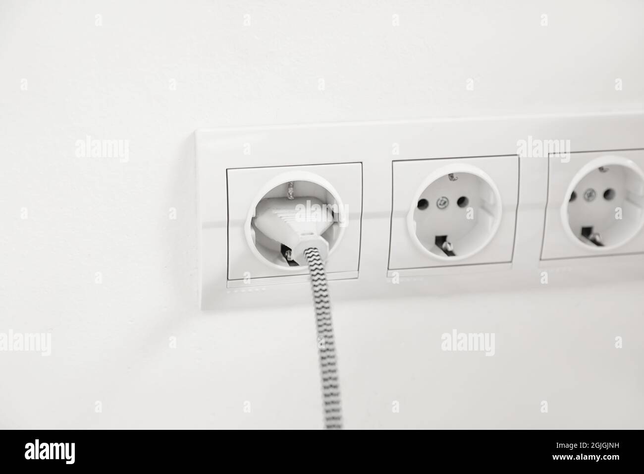 Electric socket with plug on light wall Stock Photo - Alamy