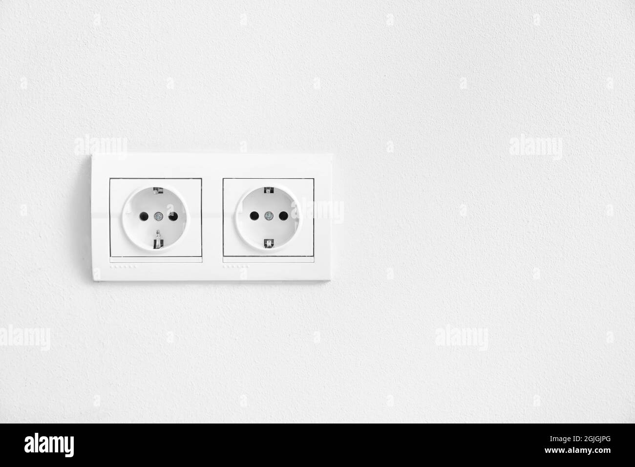 Electric socket on light wall Stock Photo - Alamy