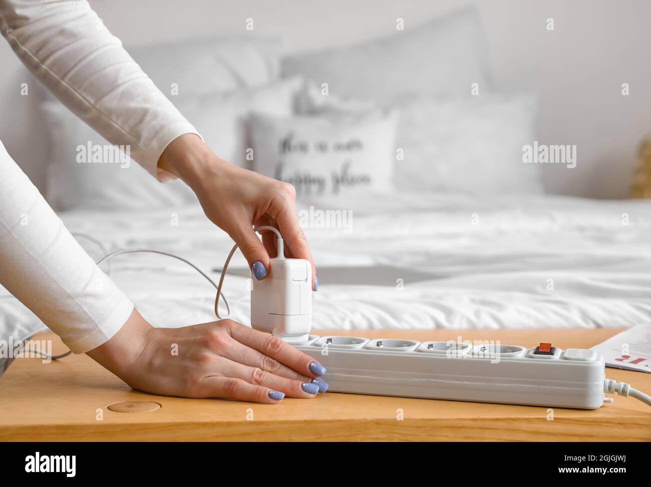 Woman putting plug into extension cord in bedroom Stock Photo - Alamy