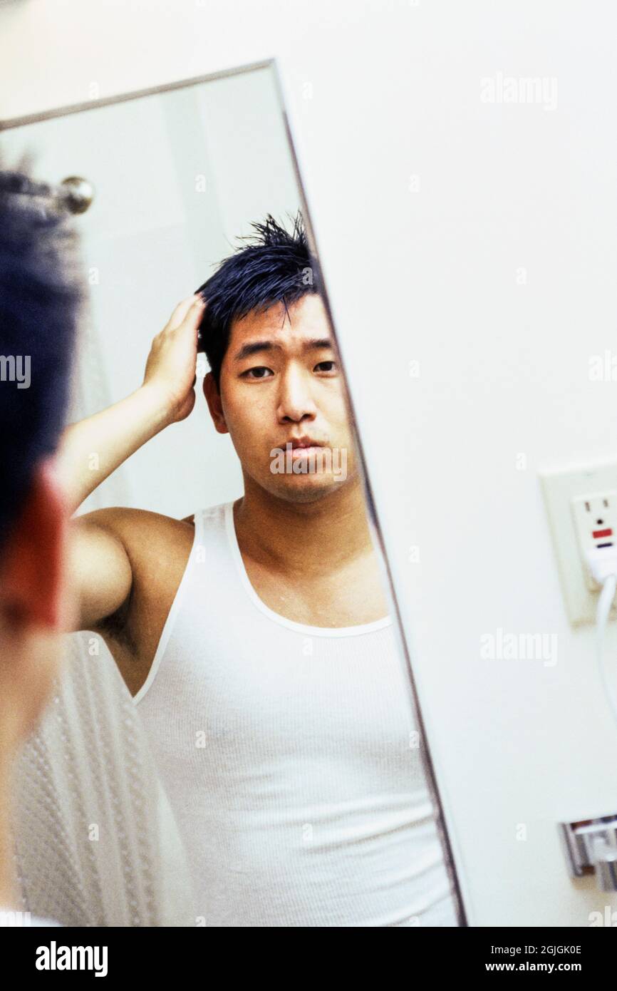 Mid 20's Asian man looking at himself in the bathroom mirror Stock ...