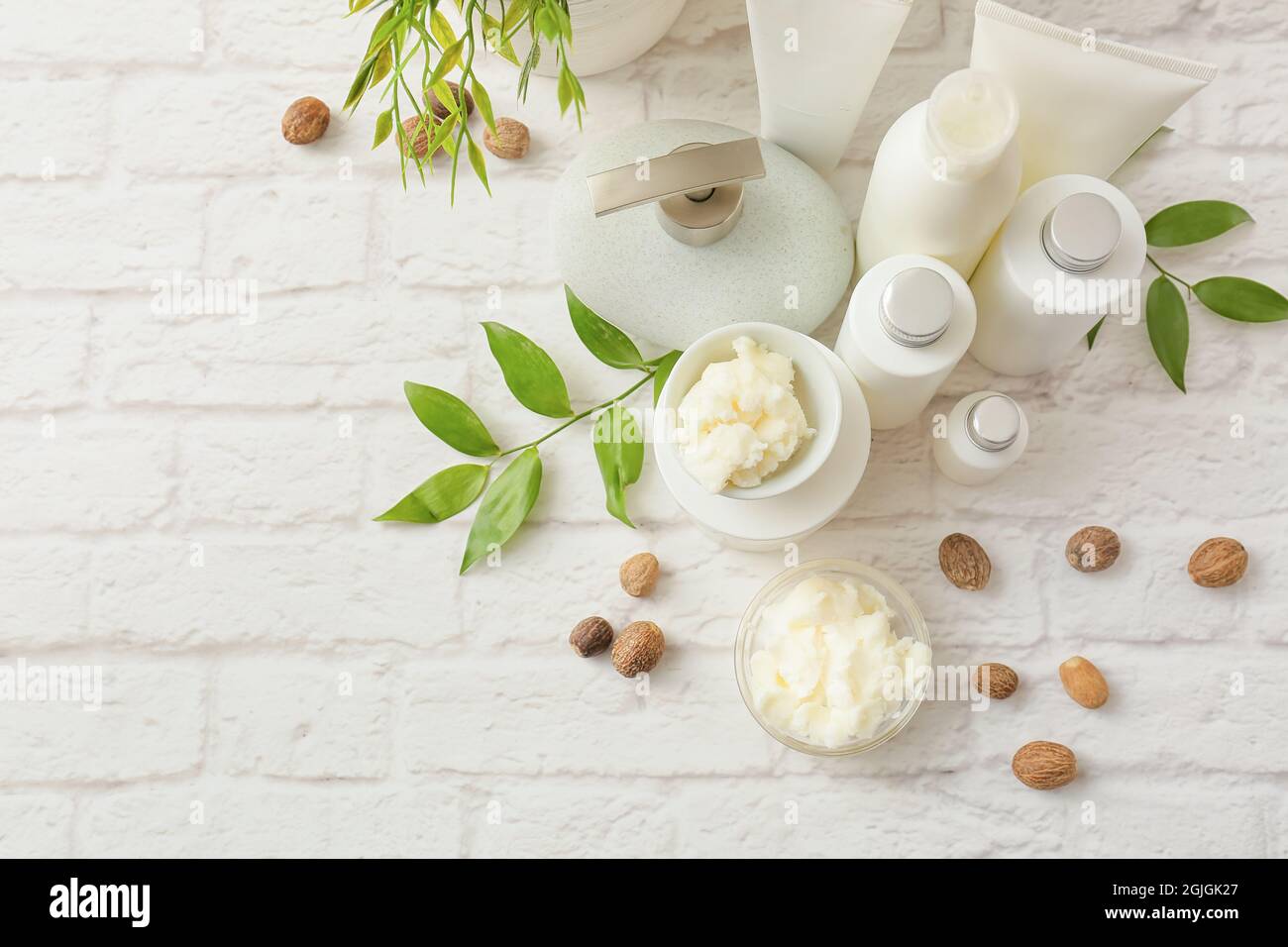 Composition with shea butter, nuts and cosmetic products on light brick ...