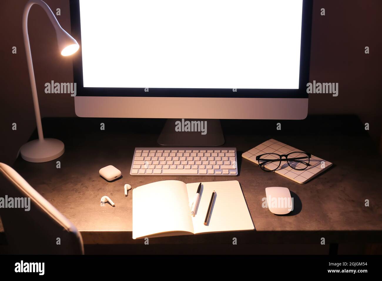 Modern workplace with computer and glowing lamp in dark room Stock ...