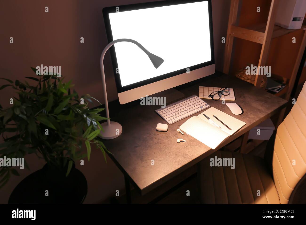 Modern workplace with computer and glowing lamp in dark room Stock ...