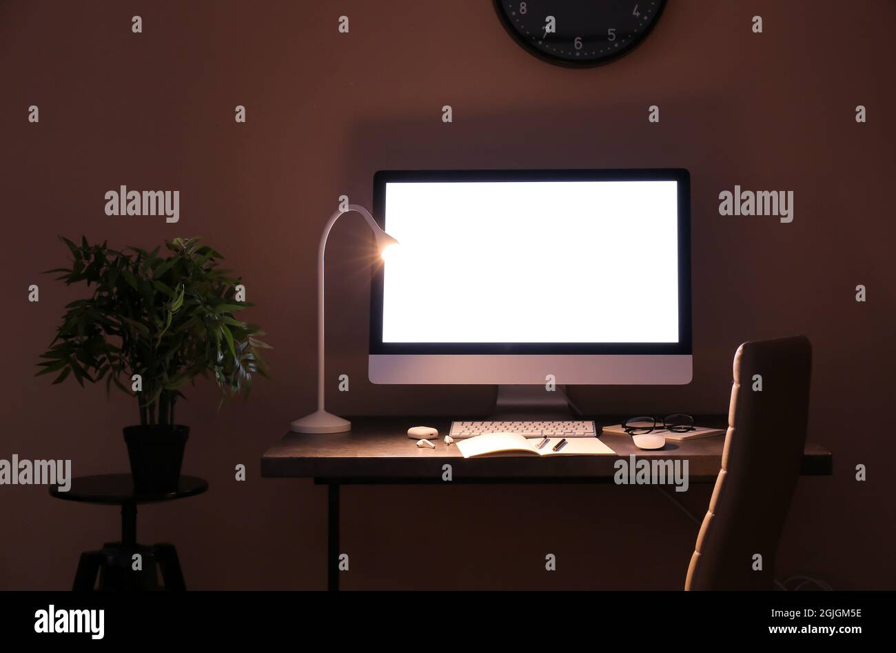 Modern workplace with computer and glowing lamp in dark room Stock ...