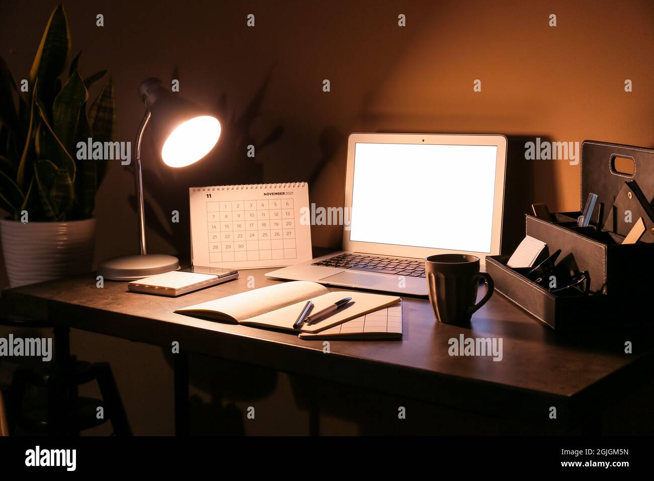 Modern workplace with computer and glowing lamp near color wall Stock ...
