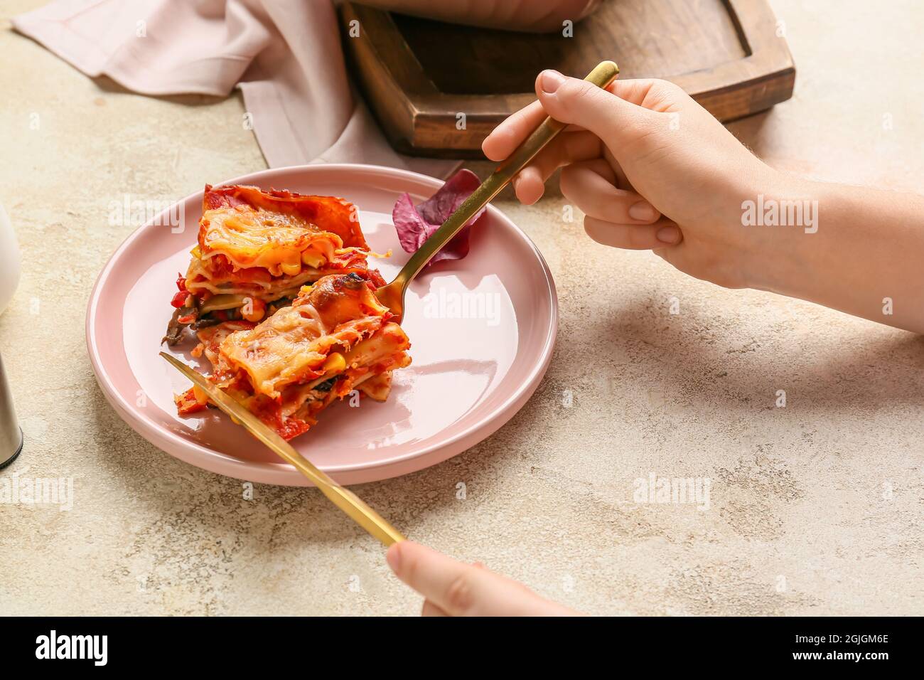 Woman eating delicious lasagna with tomato sauce on light table Stock ...