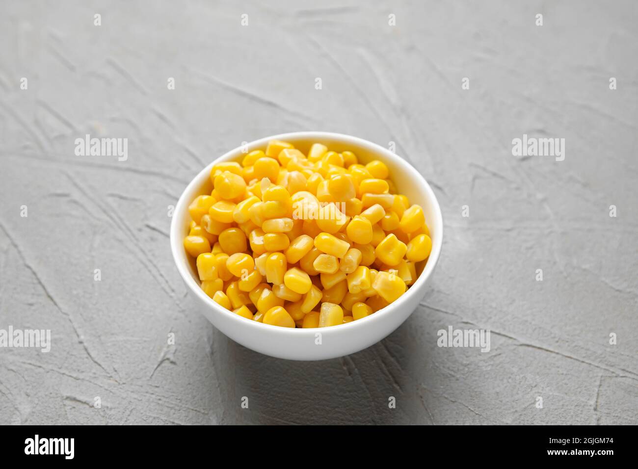 Bowl with corn kernels on grey background Stock Photo - Alamy