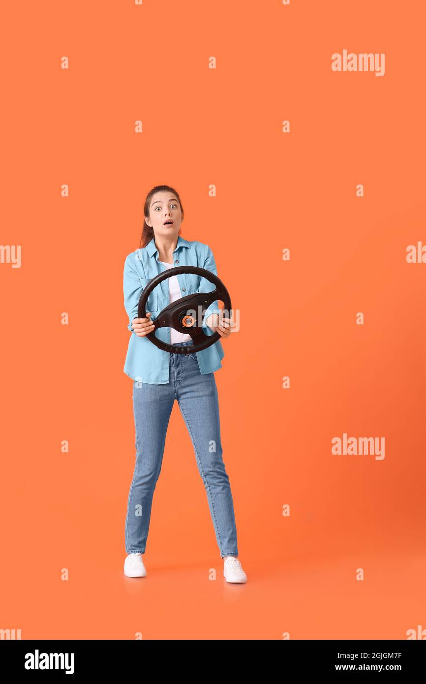 Shocked young woman with steering wheel on color background Stock Photo ...