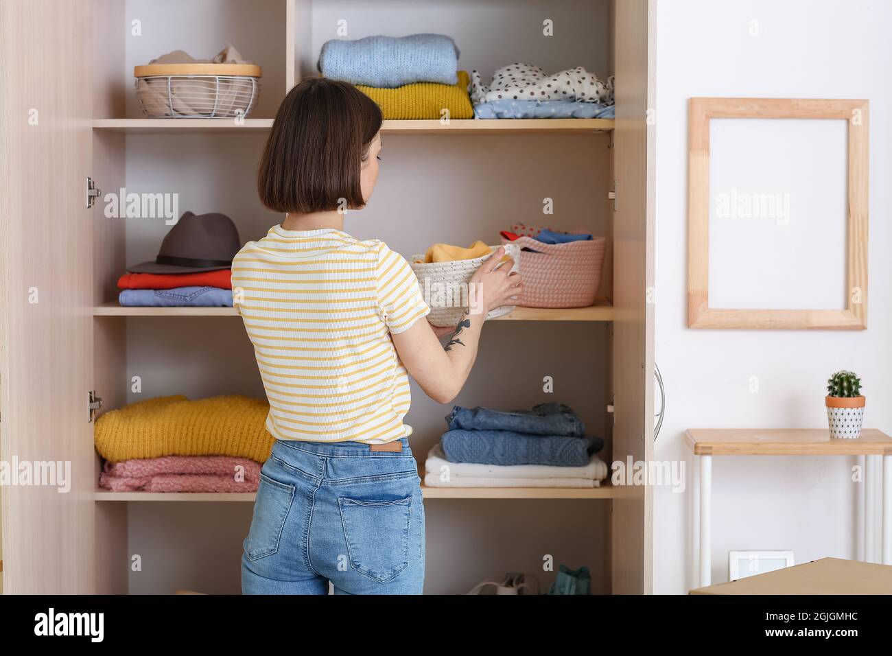 Young woman organizing clothes at wardrobe Stock Photo - Alamy