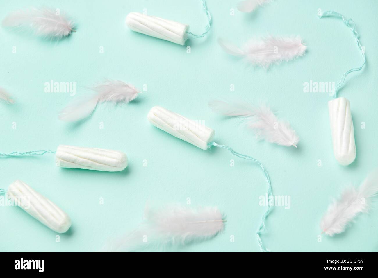 Tampons and feathers on color background Stock Photo - Alamy