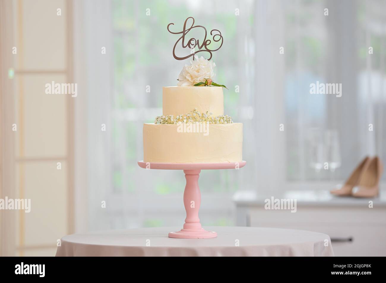 Stand with delicious wedding cake and word LOVE on table Stock Photo ...