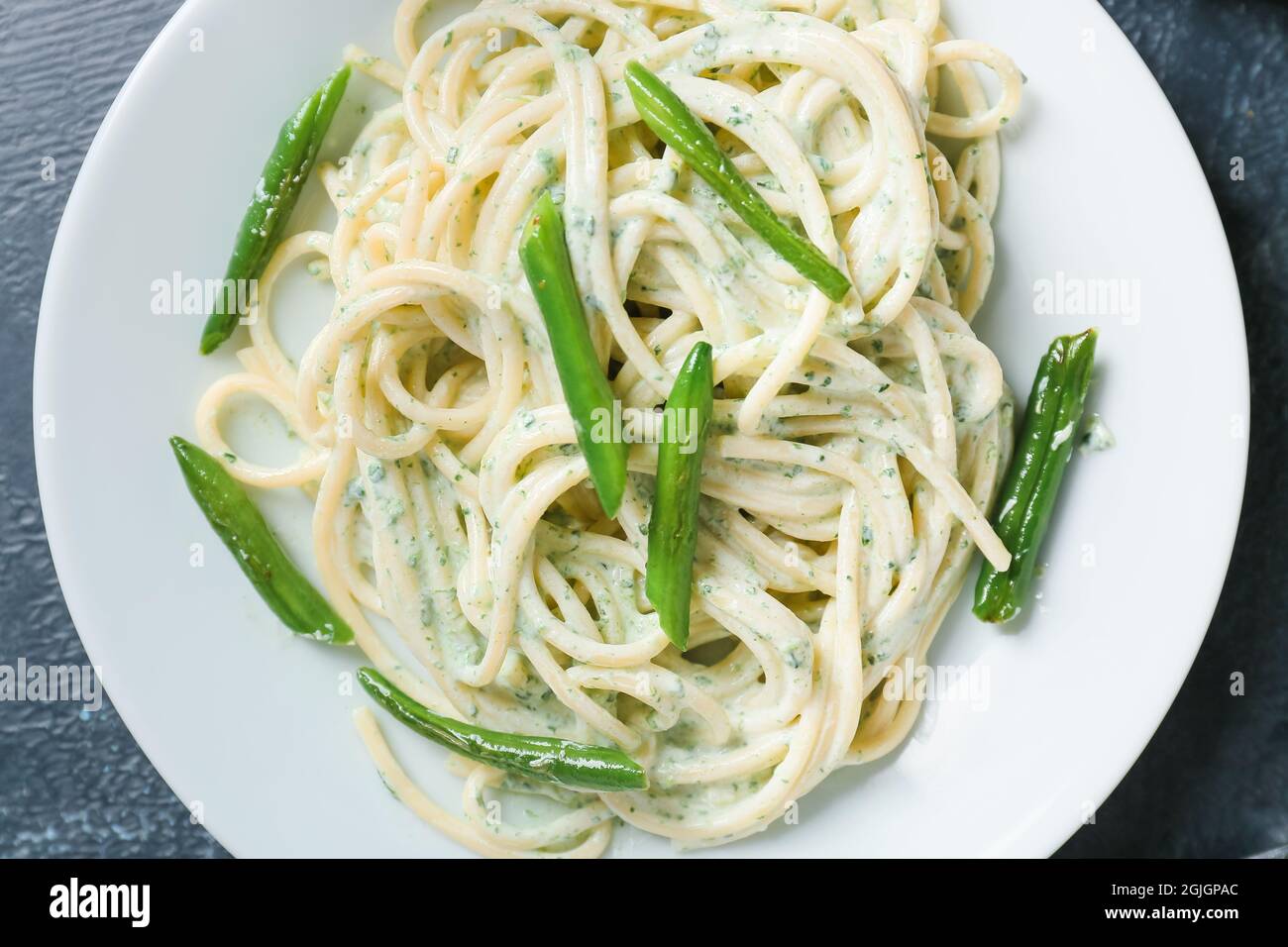 Plate of tasty pasta with green beans on dark background, closeup Stock ...