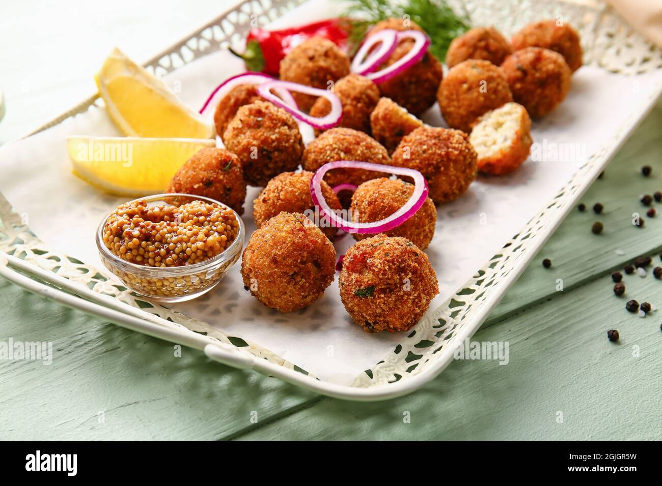 Tray with tasty cod cutlets and mustard on color wooden background ...