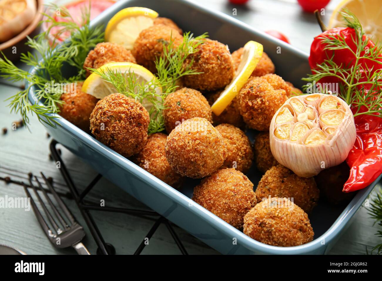 Baking dish with tasty cod cutlets on color wooden background, closeup ...
