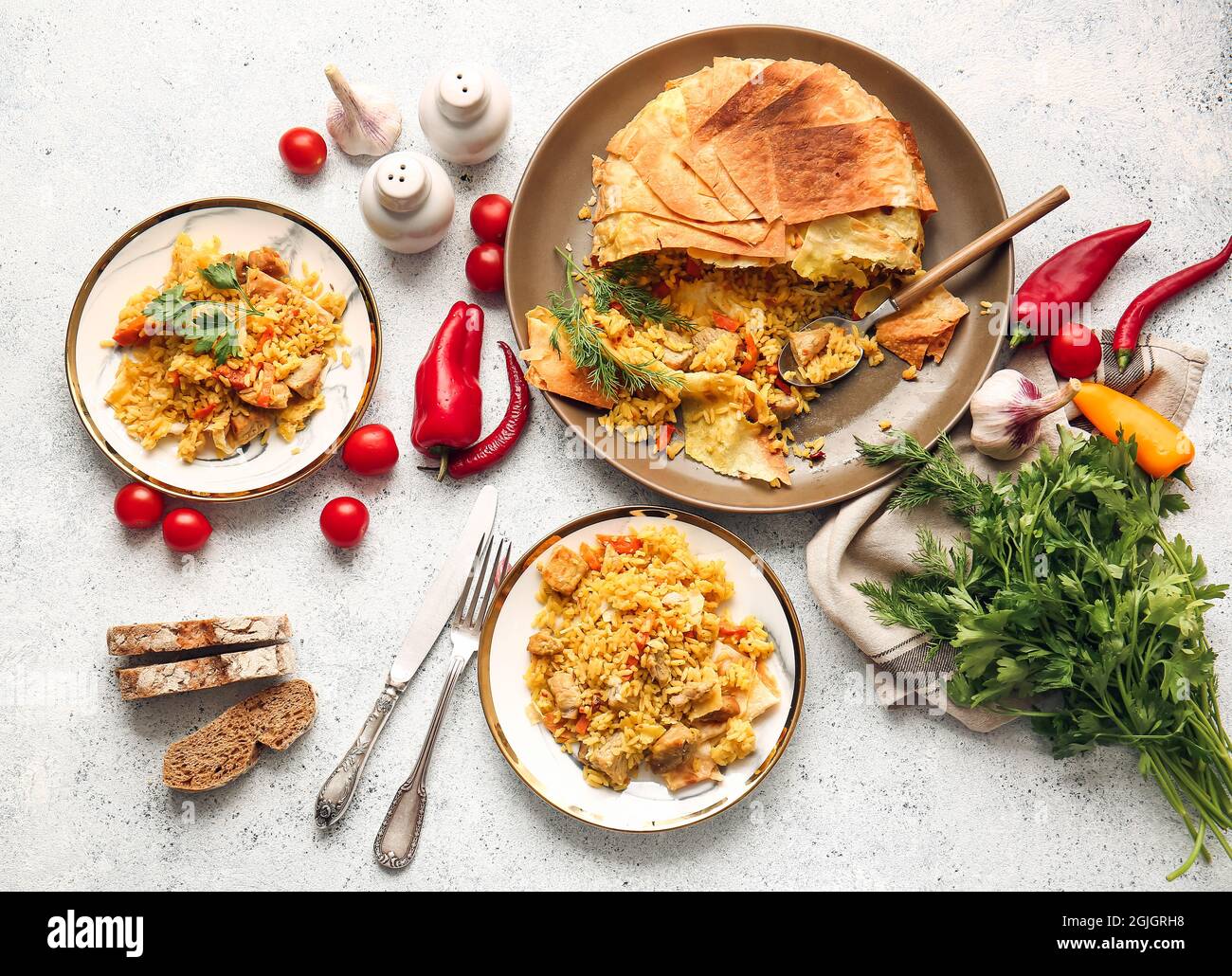 Plates with tasty Shah Pilaf, bread and vegetables on light background ...