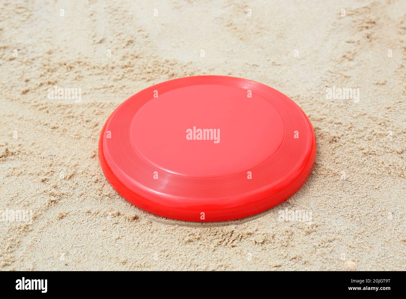 Red frisbee disk on sand Stock Photo - Alamy