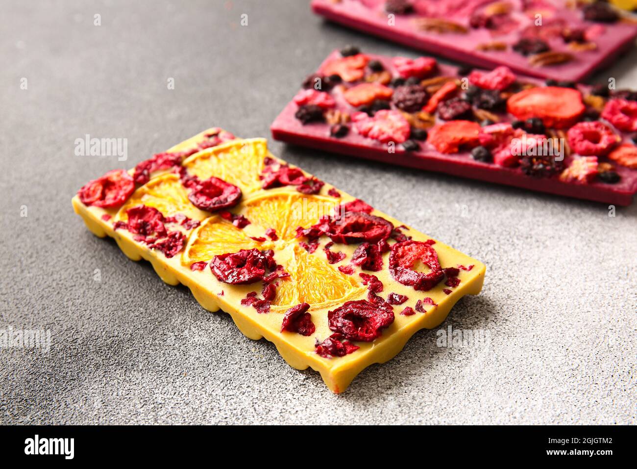 Handmade chocolate bars with fruits and berries on grey background ...
