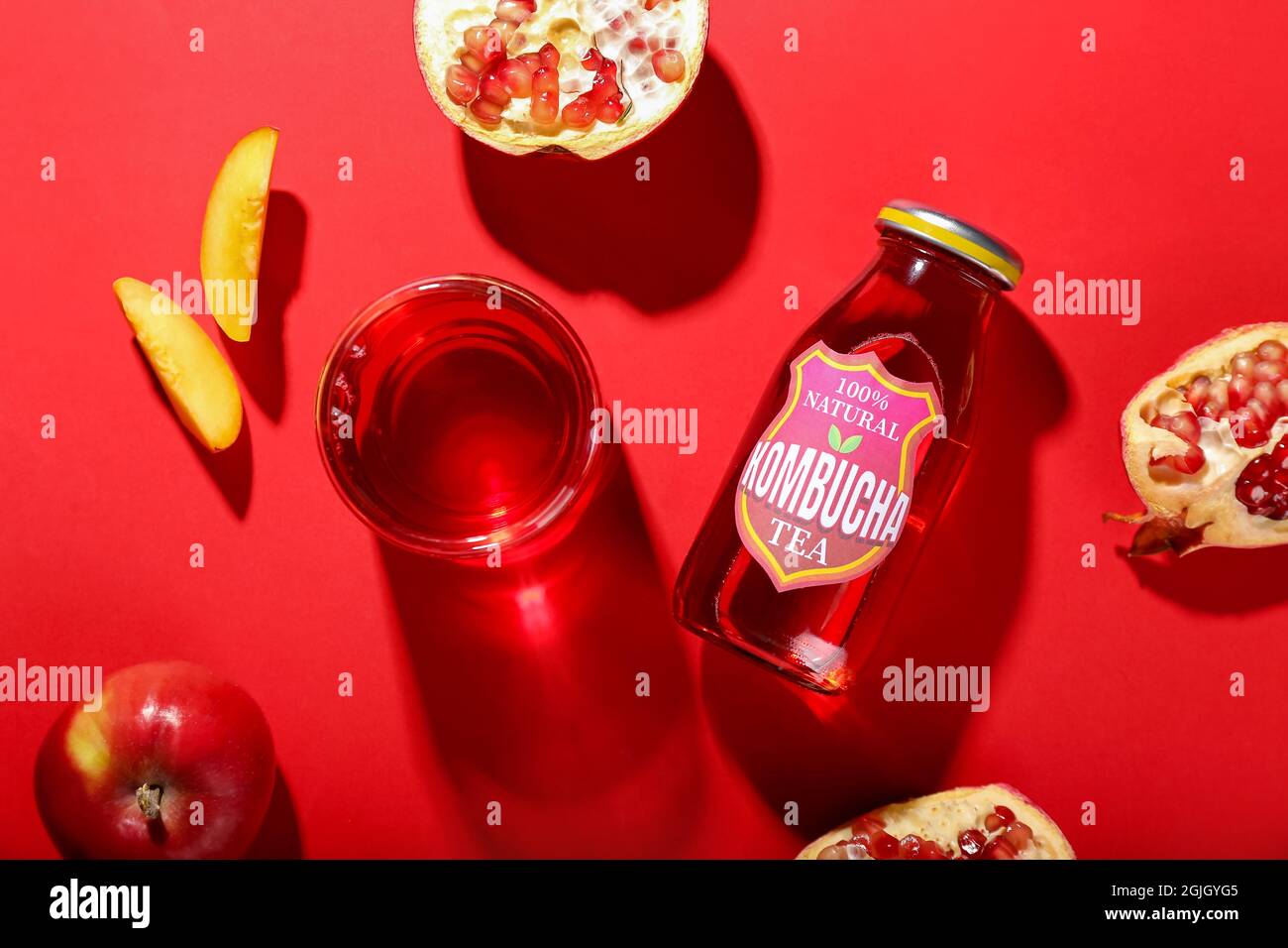 Glass and bottle of kombucha tea with fruits on red background Stock ...